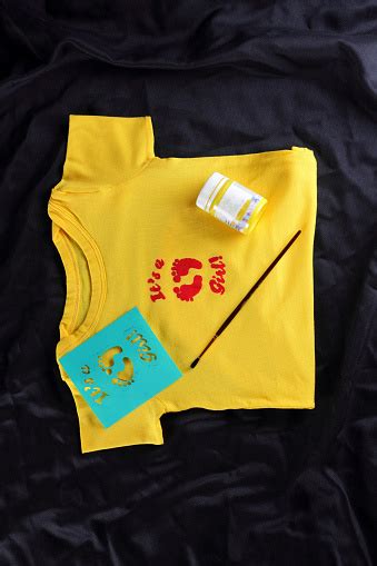 수 제 그림을 가진 아 이들의 T셔츠 봉 어두운 배경에 노란색 패브릭입니다 조정의 과정입니다 사진과 함께 티셔츠입니다 검은색에