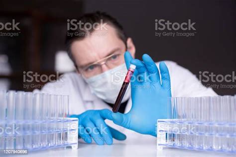 혈액 조사 마스크와 고무 장갑의 과학자는 실험실에서 테스트 튜브에서 샘플을 보고 선택한 초점 Dna에 대한 스톡 사진 및 기타