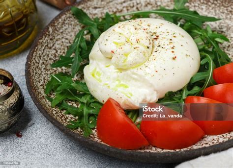신선한 Arugula 토마토 갓 갈아 낸 후추 올리브 오일과 포크 나이프 등이 포함 된 갈색 점토 플래터에 맛 있는 이탈리안 치즈를 곁들여 드 셔 보세요 모 짜 렐 라와