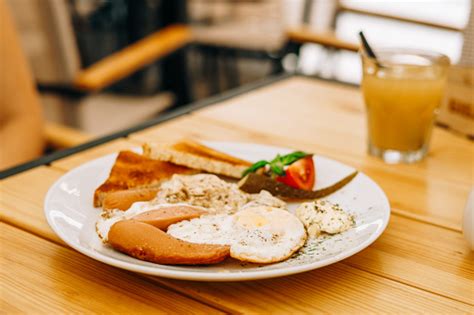 카페에서 맛있는 아침 식사 스크램블 에그와 주스 한 잔 소시지 토마토 치즈를 곁들인 스크램블 에그 흰 둥근 접시에 햄과 토스트와 스크램블 계란 0명에 대한 스톡 사진 및