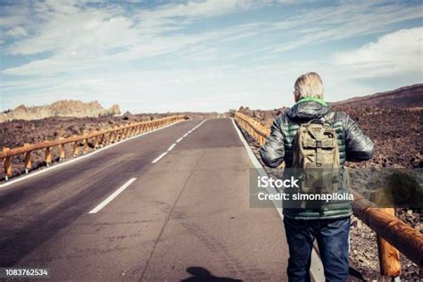 성숙한 은퇴한 남자 도보 녹색 배낭독립과 시간과 인생을 즐기는 성인 사람들에 대 한 외로운 여행자 개념 산 사막 한가운데 긴 직선 아스팔트도로에서 본 뒤따라가기 동작 활동에