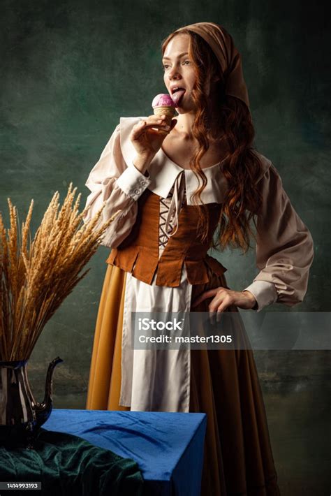 르네상스 시대의 소녀처럼 긴 곱슬 머리를 가진 매력적인 빨간 머리 소녀의 초상화 어두운 배경에 고립 된 여성 농민 시대 비교 아름다움 예술 20 24세에 대한 스톡 사진 및