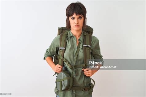 얼굴에 심각한 표정으로 고립 된 흰색 배경 위에 배낭과 물 매통을 입은 아름다운 등산객 여성 카메라를 보는 간단하고 자연스러운 심각한에 대한 스톡 사진 및 기타 이미지