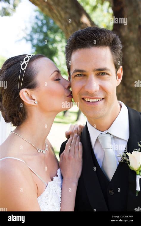 Beautiful Bride Kissing Groom On Cheek In Garden Stock Photo Alamy