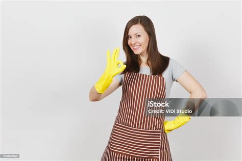 젊은 매력적인 웃는 갈색 머리 주부 스트라이프 앞치마 노란색 장갑 흰색 배경에 고립에서 아름 다운가 정부 여자 카메라를 찾고