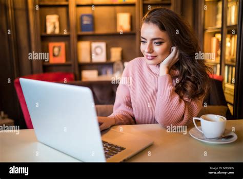 Freelance Young Woman Sitting In The Cafeteria With Laptop And Drinking
