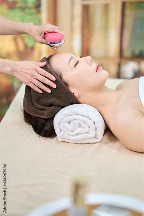 아시아 한국의 젊은 여성이 스파 또는 피부관리전문점 또는 피부과 병원에서 침대에 누워 눈을 감고 고주파마사지 미용기계로 전문관리사에게 얼굴부분에 리프팅 또는 주름관리를 받고