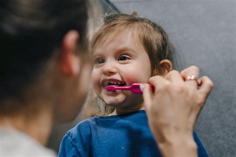 행복한 엄마와 아이 어린 소녀가 욕실에서 칫솔로 이를 닦고 있다 행복하고 사랑하고 돌보는 엄마는 아이에게 치과에 대해 가르치고 아침에 입을 닦는다 2 3 살에 대한 스톡
