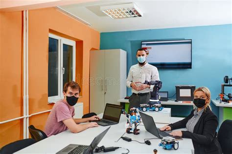 A Group Of Colleagues Working Together In A Robotics Laboratory Focusing On The Intricate