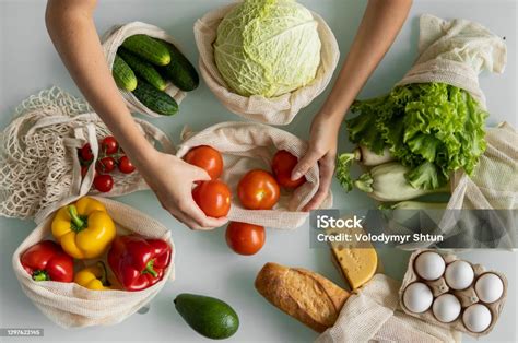 여성의 손은 집에서 부엌에서 채소가 있는 재사용 가능한 식료품 가방을 들고 토마토를 꺼낸다 제로 폐기물 및 플라스틱 무료 개념