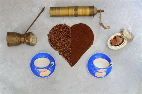 커피 원두와 분쇄 커피를 갈색 배경에 나무 숟가락으로 빻습니다 커피 포트 블루 커피 컵 및 커피 그라인더가 있습니다 밝은 돌