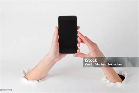 흰색 배경의 찢어진 구멍을 통해 스마트 폰을 들고 여성의 손 크리에이티브 아트 개념에 대한 스톡 사진 및 기타 이미지 개념 개념과 주제 공란 Istock