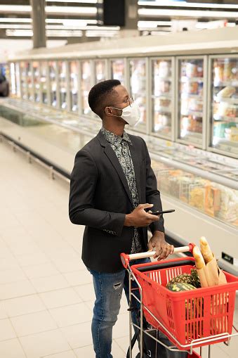 냉동 식품으로 큰 디스플레이 옆에 서 있는 보호 마스크를 쓴 젊은 사업가 남자에 대한 스톡 사진 및 기타 이미지 남자 소매 소비자주의 쇼핑 카트 Istock