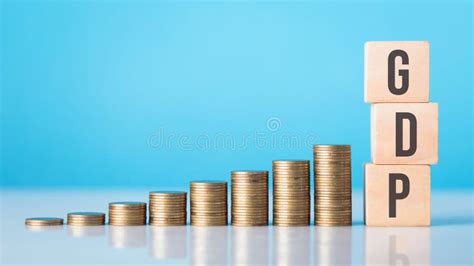 A Wooden Block Labeled Gdp Next To A Stack Of Coins Arranged From