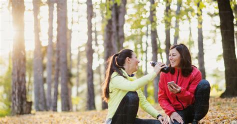 스마트폰과 물병을 든 두 명의 여성 주자가 가을 자연 속에서 숲 속 야외 바닥에 앉아 쉬고 있다 사진 Unsplash의 노인 성인 이미지