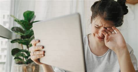 격리 기간 동안 집에 앉아 있는 동안 태블릿의 나쁜 소식에 울고 있는 슬픈 소녀 젊은 여성은 직장을 잃었고 우울하고 걱정스러운 반응을 보였습니다 실업과 경제 위기