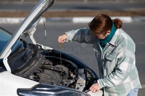 Caucasian Female Driver Checking Oil Level In Car Engine Stock Image