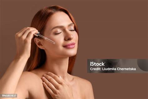 아름 다운 젊은 여자가 갈색 배경에 그녀의 얼굴에 화장품 혈청을 적용 텍스트 공간 사람 얼굴에 대한 스톡 사진 및 기타 이미지 사람 얼굴 에센셜 오일 피부 Istock