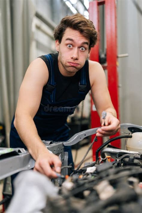 Vertical Portrait Of Frustrated Mechanic Male In Auto Shop Working To