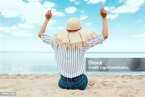 모래 사장에 앉아 넓은 팔으로 밀 짚 모자에 있는 여자의 후면 보기 관광에 대한 스톡 사진 및 기타 이미지 관광 관광객 몸짓 Istock