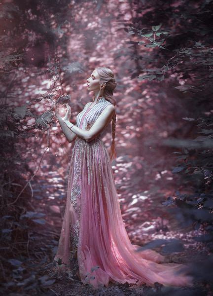 جادوگر اسرارآمیز در لباس آبی زیبا پس زمینه یک جنگل سرد در مه است دختر با یک جغد سفید عکاسی هنری