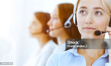 햇볕이 잘 드는 사무실에서 일하는 다양한 전화 사업자 그룹 헤드폰 컨설팅 클라이언트와 잘 생긴 비즈니스 여성 콜센터 및 비즈니스