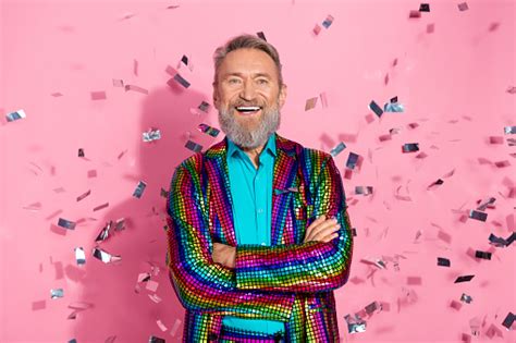 우아한 양복을 입은 카리스마 넘치는 노인이 분홍색 배경에 미소를 지으며 활기찬 색종이 조각으로 재미 있고 축제 분위기에서 축하합니다 60 64세에 대한 스톡 사진 및 기타