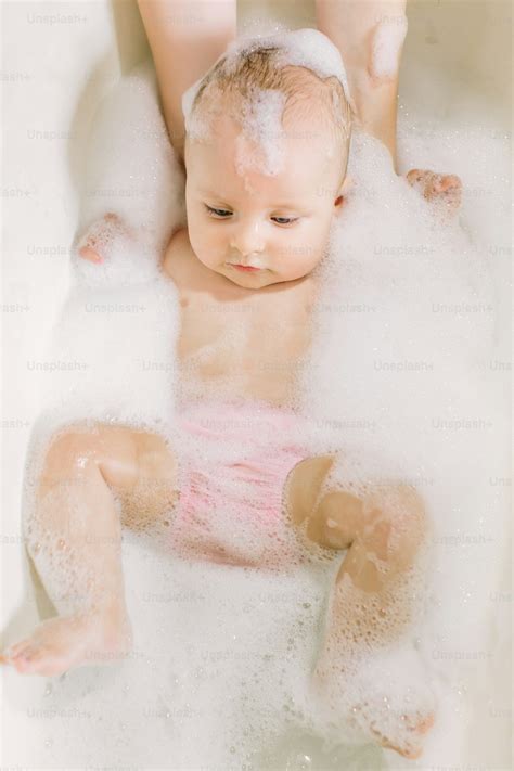거품 거품을 가지고 노는 목욕을 하는 행복한 웃는 아기 욕조에 있는 어린 아이 화려한 장난감 오리와 함께 욕실에서 웃는 아이 유아 씻기 및 목욕 어린 아이들을위한