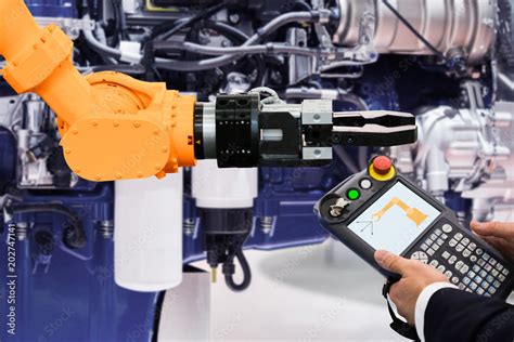 Engineer With Teach Pendant Device Programming Robot With Robotic Arm
