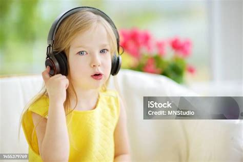 거대한 무선 헤드폰을 착용 하 고 귀여운 소녀입니다 음악을 듣고 있는 예쁜 아이 여학생은 집에서 아이들의 노래를 듣고 재미있게