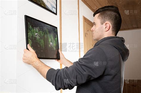 把一幅画挂在墙上的人