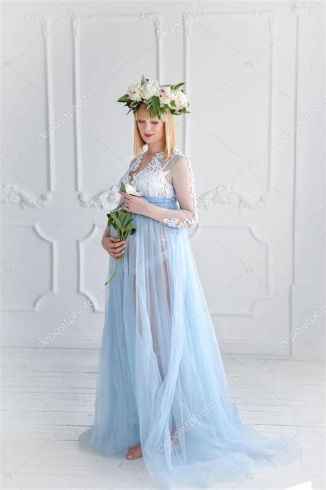 Beautiful Pregnant Woman In Light Blue Dress With Flower Diadem In White Room Stock Photo By
