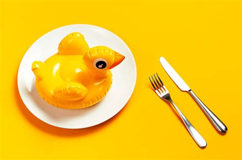 팽창식 미니 옐로우 치킨 또는 흰색 접시에 오리 노란색 배경에 포크 나이프 창조적 인 음식 개념 담배 치킨 수영을위한 추세 풍선 어린이 장난감 설계를 위한 레이아웃 0명에
