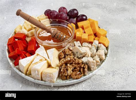 Appetizer Assorted Cheese With Nuts And Honey On A Round Plate Top