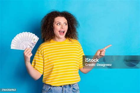 매력적인 젊은 여자의 사진 돈 부채 보기 포인트 빈 공간 옷을 입은 줄무늬 노란색 옷 파란색 배경에 고립 된 가리키기에 대한 스톡 사진 및 기타 이미지 Istock