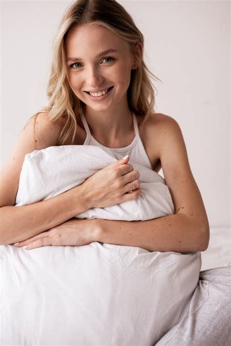 Portrait Of Beautiful Young Blonde Woman Hugging White Pillow Sitting