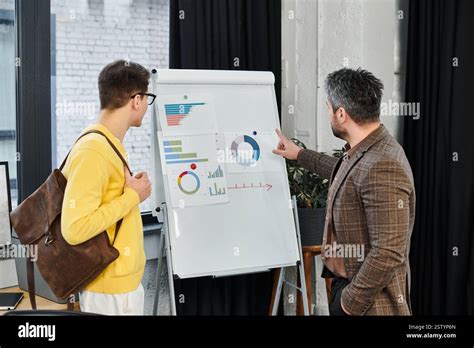 Two Colleagues Engage In An Onboarding Session Discussing Charts And Data In The Office Space