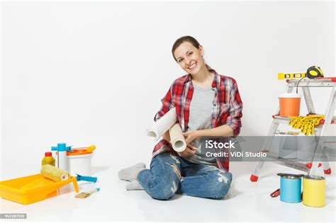 벽지와 바닥에 앉아 캐주얼 옷에서 여자 롤 흰색 배경에 고립 된 재건축 아파트에 대 한 악기 페인팅 도구를 붙이기 위한 액세서리입니다 수리 가정 개념입니다 공간 복사 개선에