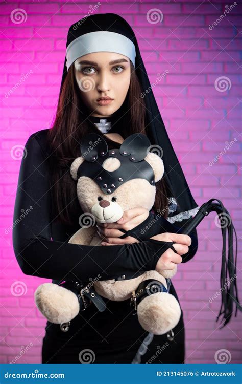 A Woman In A Nun Costume With A Teddy Bear Dressed In Accessories For