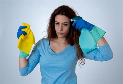 아름다운 화가 난 여자는 걸레를 들고 스프레이를 청소하는 것은 국내 의무 개념과 성별 고정 관념에 좌절과 분노를 느낀다 파란색 배경에 격리 된 스튜디오 초상화입니다 가사