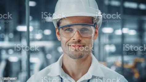 자동차 조립 공장에서 사무실에서 안전 고글과 흰색 하드 햇을 입고 젊은 잘 생긴 자신감 엔지니어의 초상화 현대 공장에서 차량 생산에 종사하는 산업 전문가 보호안경 보호용