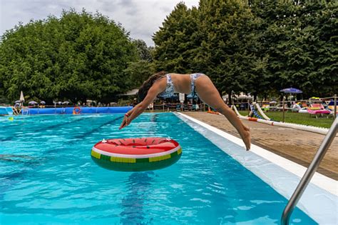 수영복을 입은 젊은 여자가 수영장 가장자리에서 빨간 둥근 구명 부표로 장난스럽게 다이빙 25 29세에 대한 스톡 사진 및 기타 이미지 25 29세 감정 공기 주입