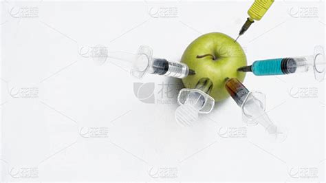 杀虫剂、硝酸盐、转基因和其他化学物质被用注射器注射到青苹果中。前视图。
