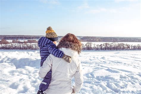 뒷 전망 어머니는 36 세의 소년의 어린 아이를 팔에 들고 겨울에는 도시에서 오후에 자연에서 텍스트를 위한 여유 공간 숲 드리프트와 눈 배경 12월에 대한 스톡 사진 및