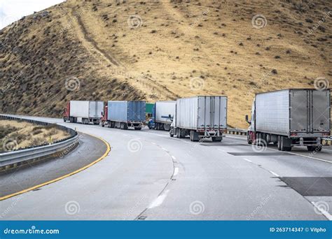 Big Rigs Semi Trucks With Loaded Semi Trailers Slowly Climbing Uphill