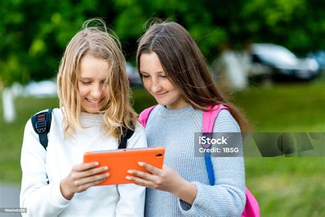 두 여자 친구 여 학생입니다 자연에서 여름입니다 그녀의 손에 태블릿을 보유 하고있다 뒤에 가방 소셜 네트워크에서 비디오를 보고의 개념입니다 감정 하 고 행복 하 게 웃