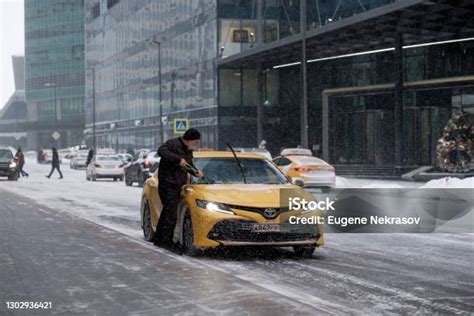택시 기사가 얼음과 눈에서 앞유리와 와이퍼 브러시를 청소합니다 Toyota Camry에 대한 스톡 사진 및 기타 이미지