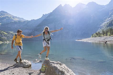 아름다운 고산 호수 옆에서 손을 잡고 바위에서 바위로 점프하는 두 명의 등산객 스위스에 대한 스톡 사진 및 기타 이미지 스위스 커플 하이킹 Istock