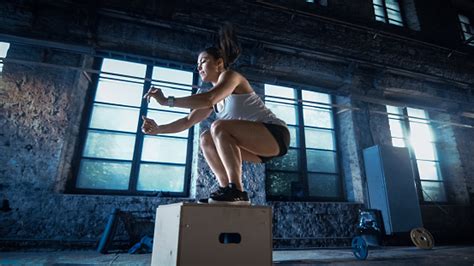 그녀의 운동을 하는 동안 전투 로프와 함께 연습 하는 체육관에서 운동 여성 고 강도 간격 훈련 그녀는 근육 등이 희미하게 땀이 체육관 산업 빌딩에 있다 고강도 인터벌