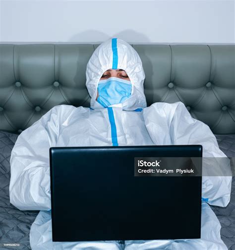 의료용 보호복 고글 마스크 장갑을 끼고 노트북 작업을 하는 의사가 집 침대에 누워 있다 바이러스 전염병에 의한 보호 메르스 코로나 바이러스 의료 개념입니다 25 29세에